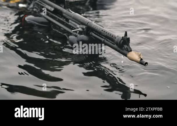 Combat swimmer with a machine gun in hands appears in river waters in ...