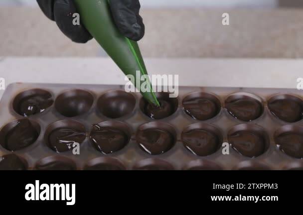 Bakers hands pouring liquid chocolate filling praline in form from ...