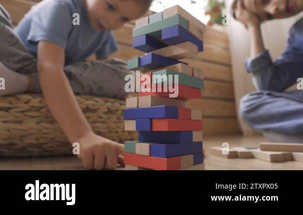 Two boys brothers are building a tower from wooden blocks sitting on ...