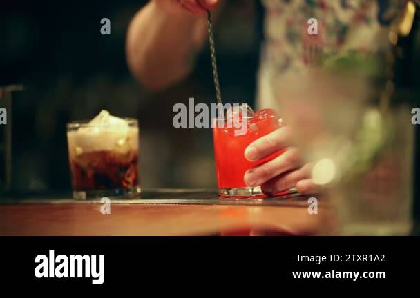 Bartender working. Mixing an alcoholic cocktail in the glass using a ...
