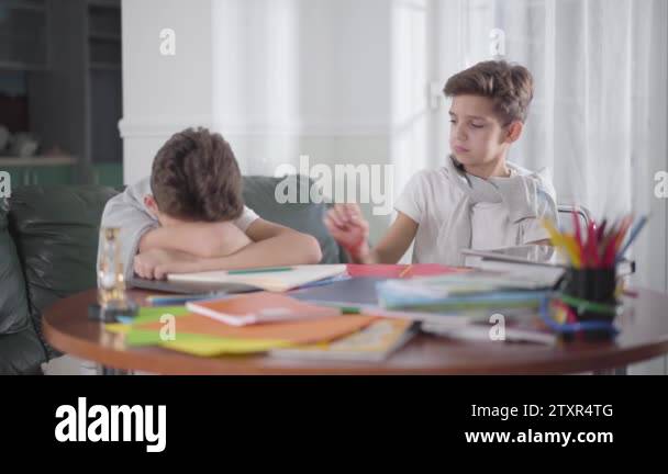 Cute Caucasian boy waking up his twin brother sitting at the table ...
