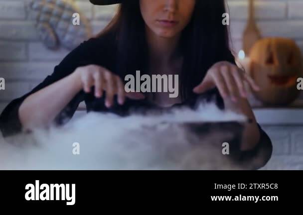 Scary witch making magic potions in her pot with white smoke, Halloween ...