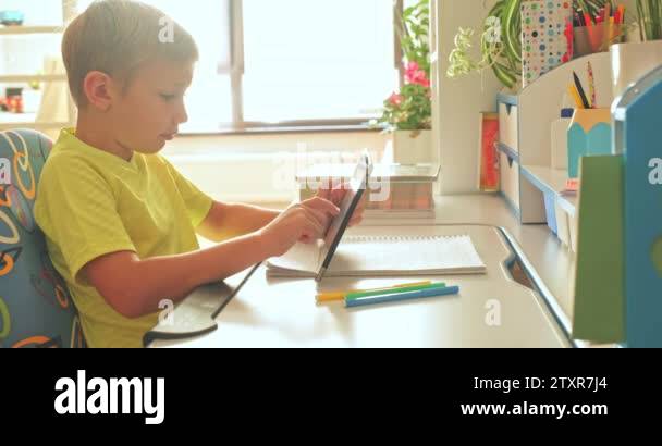 Schoolboy with tablet at home. Boy looks to the screen tablet ...