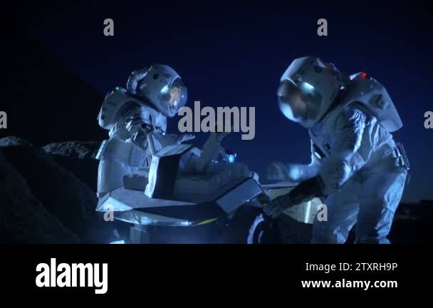 Two Astronauts in Space Suits on an Alien Planet Prepare Space Rover for Surface Exploration ...