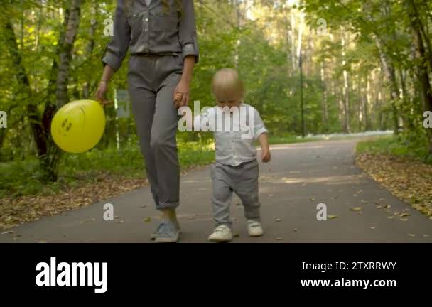 Mother and her son walking hand in hand. Young woman and funny baby in ...