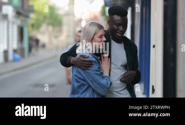 A man and woman standing outside a shop window together, he has his arm ...