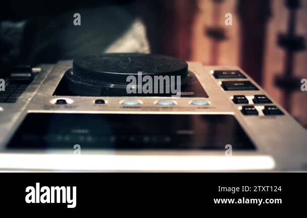 DJ at a console booth spinning and touching mixer faders and knobs ...