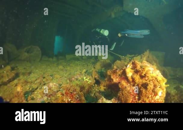 Diver inside hull of sunken ship underwater of Pacific Ocean on Chuuk ...