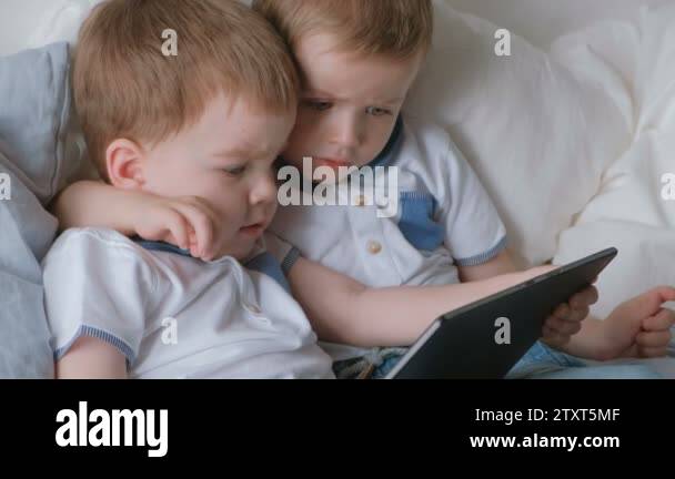 Kids with tablet. Two boys twins toddlers looking cartoon at tablet ...