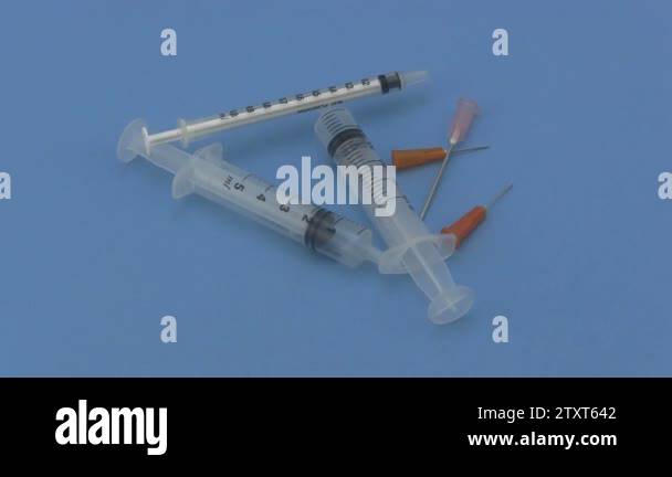Hypodermic syringe and needle rotating on a blue background Stock Video ...