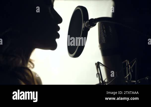 Woman singing in the recording studio. Profile of a woman with a ...