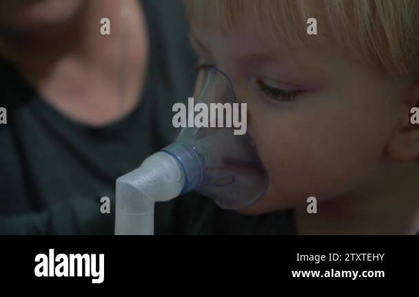 A child of three years old breathing in an oxygen mask. Inhalation of ...