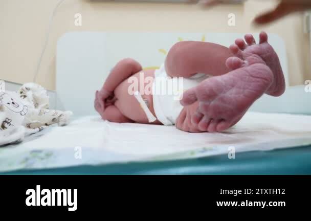 Newborn baby girl lying on back. Baby is kicking and stretching legs ...