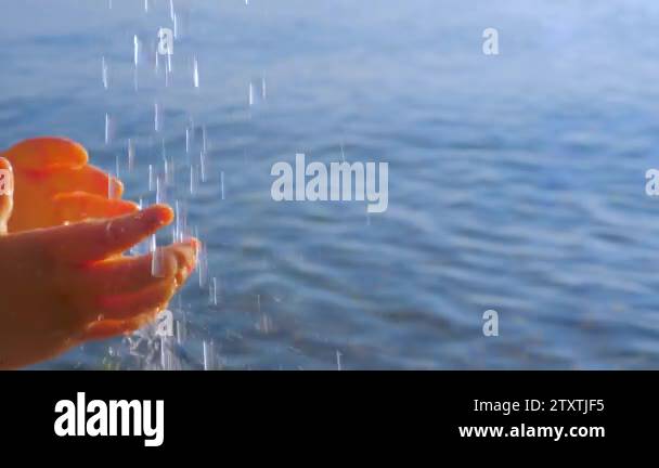 Kids hands reaching out the drops of the water. Water pouring from the ...