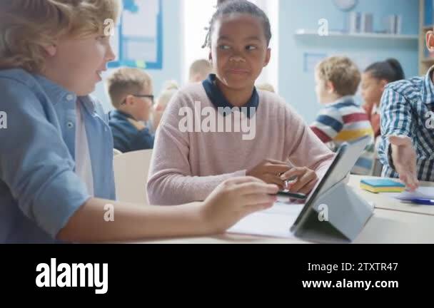 In the Elementary School: Girl and a Boy Work as a Team Using Tablet ...