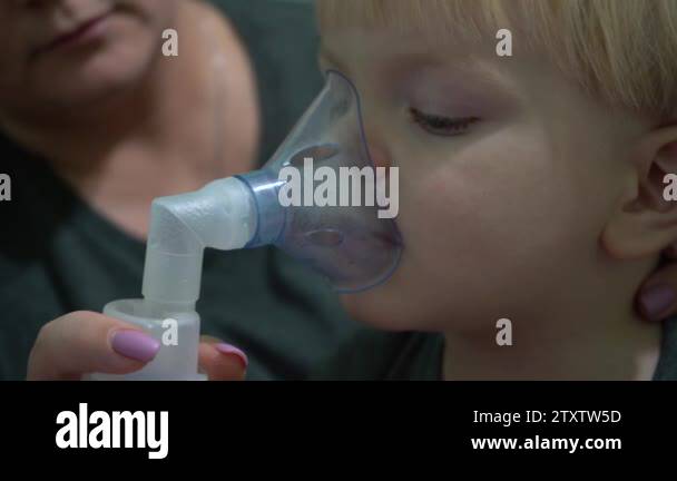 A child of three years old breathing in an oxygen mask. Inhalation of ...