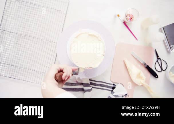 Step by step. Flat lay. Icing tall birthday cake with white buttercream ...