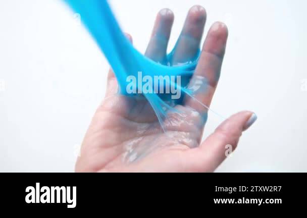 Girl stretching blue slime to the sides. Woman hands playing slime toy ...