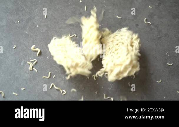 A block of Asian ramen instant noodles dropping and cracks on table ...