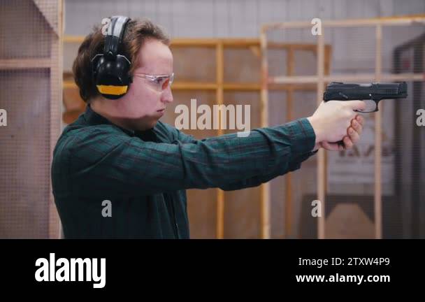 Shooting gallery. A concentrated young man shooting on a shooting range ...