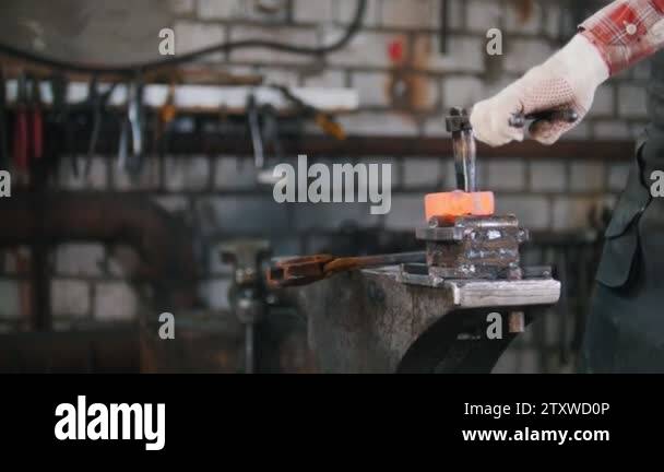 Blacksmith workroom. Making a detail using a hammer and a chisel ...