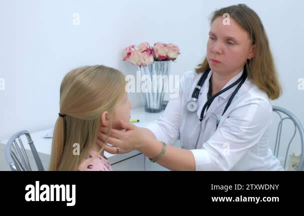 Pediatrician woman probing lymph nodes on neck of girl child during ...