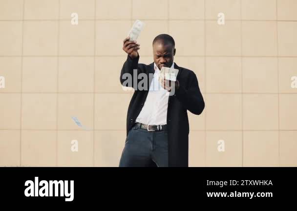 Young happy businessman scatter the dollars and funny dancing in the ...