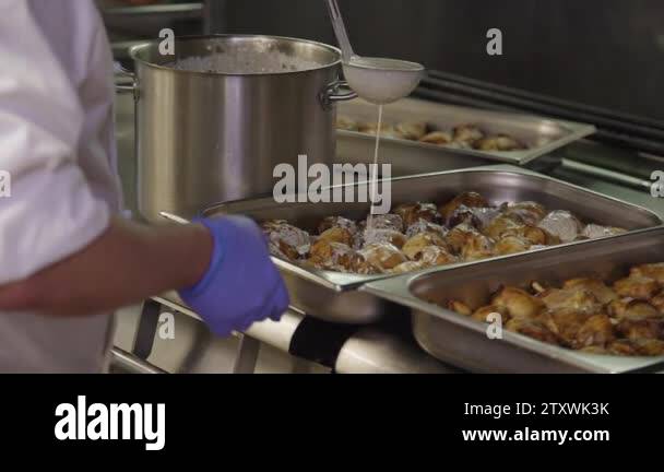 closeup. chef hand pouring baked chicken with white sour cream sause in ...