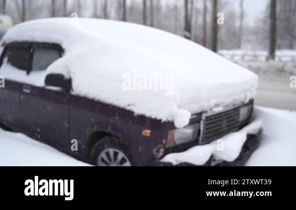 a car's front part buried in snow after a blizzard. Car covered with ...