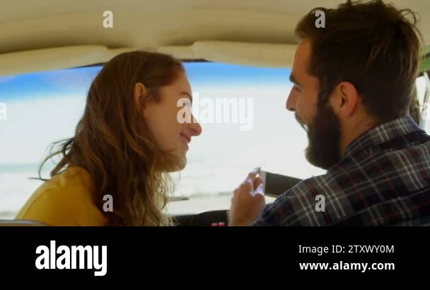 Happy young couple interacting with each other in van. Having fun on ...