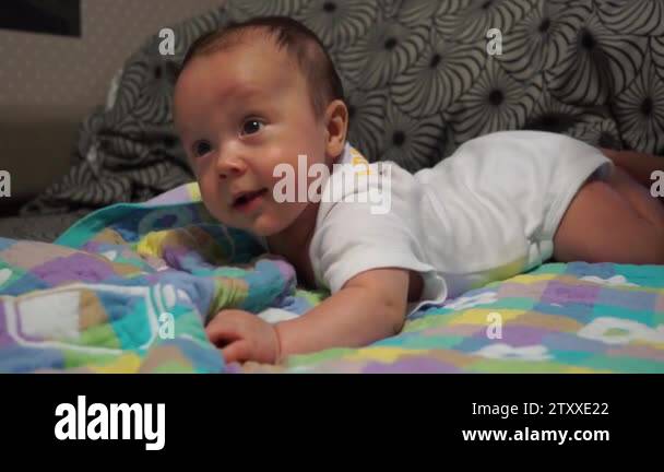 Adorable happy little baby boy three month old lying on his stomach on ...