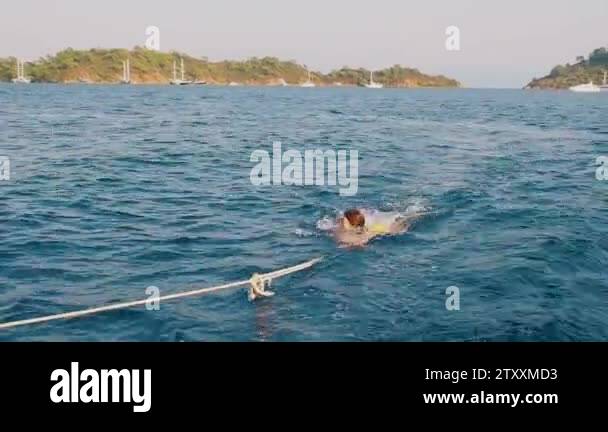 pulled out of the water on Board a boat, a young woman swims behind a ...