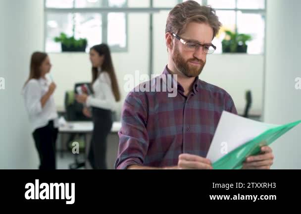 Bearded manager checks information looking in papers standing in the ...