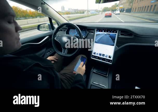 Man sits in an electric car going on autopilot. Futuristic automated ...
