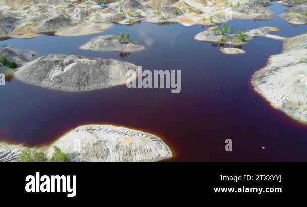 motion over quiet dark lake in old spent clay quarry with white islands ...