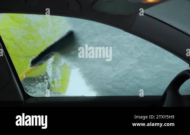 Scraping snow and ice from car windshield. Windshield wipers raised the ...
