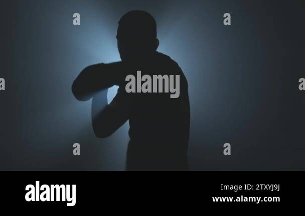 Boxer training in low light gym. Sportsman boxing in camera. Silhouette ...