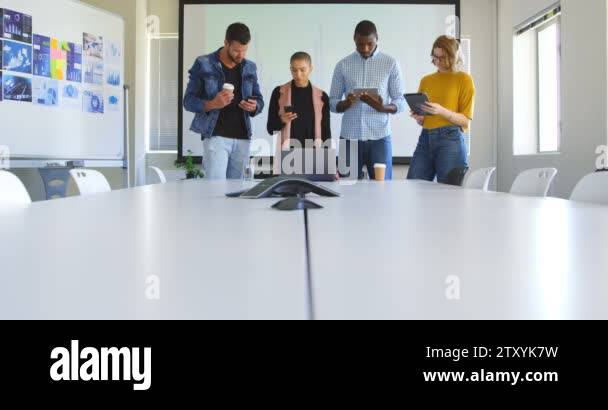 Front view of mixed race business team working on multimedia devices in ...
