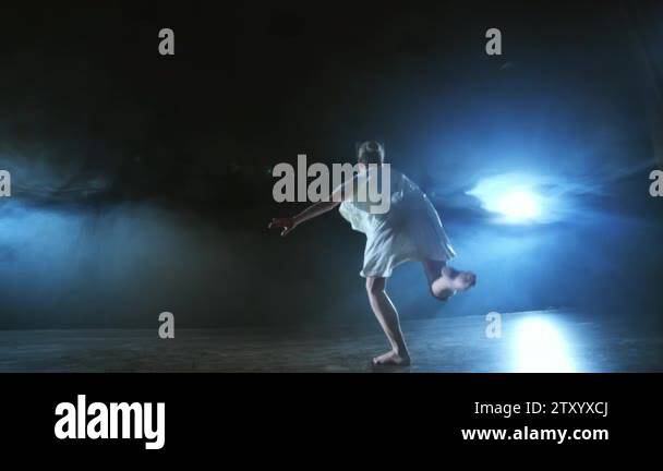 A dramatic scene of modern ballet, a lone ballerina in a white dress ...