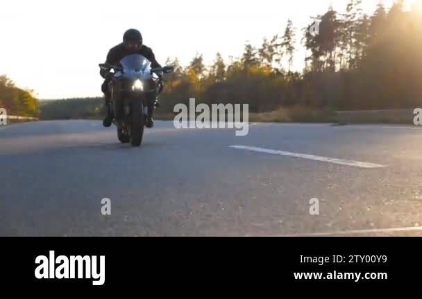 Front view of young man in helmet riding fast on modern sport motorbike ...