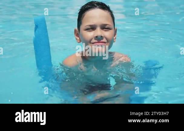 Smiling boy swimming with big plastic tubes in a paddling pool in slo ...