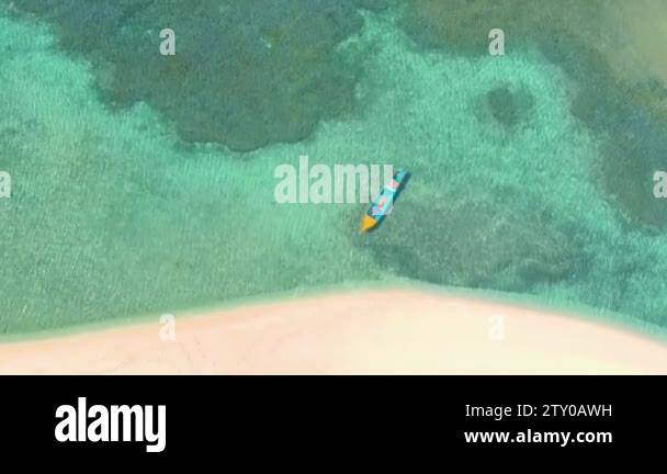 4K Tropical landscape of white sandy beach and coral reefs. Small boat ...
