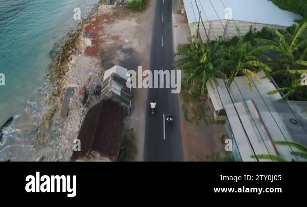 Man riding a motorcycle with surfboard by road near beautiful rice ...