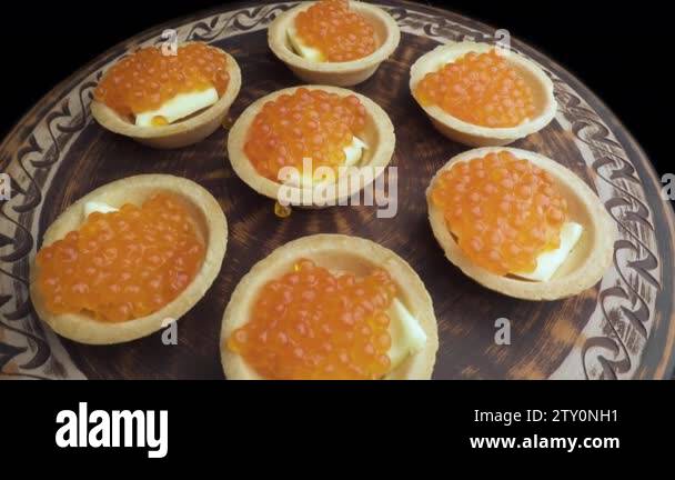 Red caviar is put with a spoon on tartlets. Preparation of snacks with ...