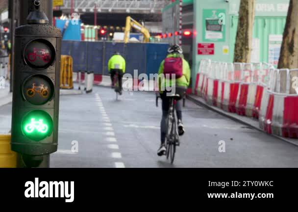 Cyclists ride in a busy cycle lane in London with cycle traffic lights ...