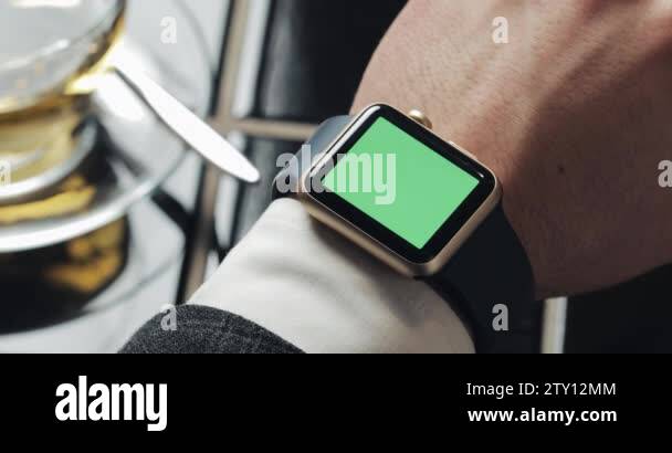 Close up man hands gestures on a modern smartwatch use with a green ...