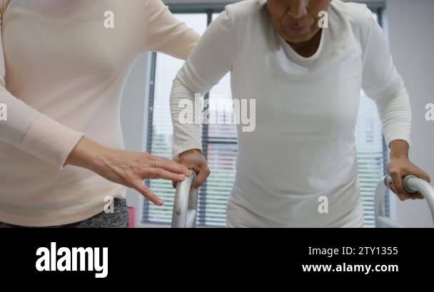 Front view close up of a Caucasian female physiotherapist helping a mixed race female patient ...