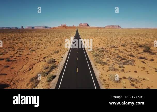 drone flying backwards over iconic empty sandstone desert road in ...