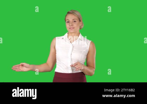 Woman blonde walking and talking to camera pointing to sides on a Green ...