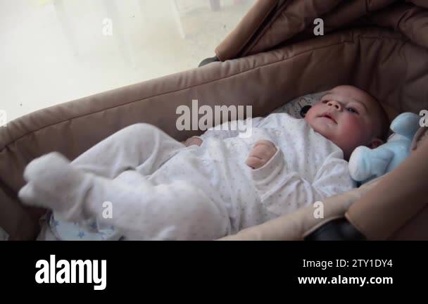 cute 3 months old baby boy making funny faces in baby carry cot Stock ...